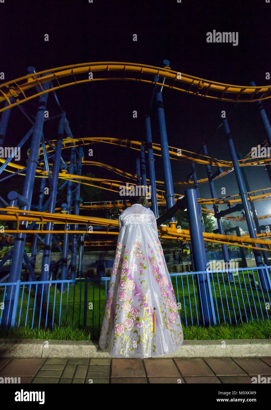 North Korean woman in choson-ot in front of a roller coaster at Kaeson ...