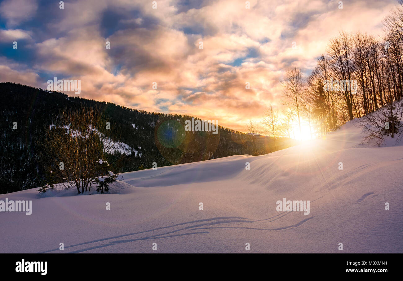 sun rising behind the snowy slope. wonderful nature winter scenery in ...