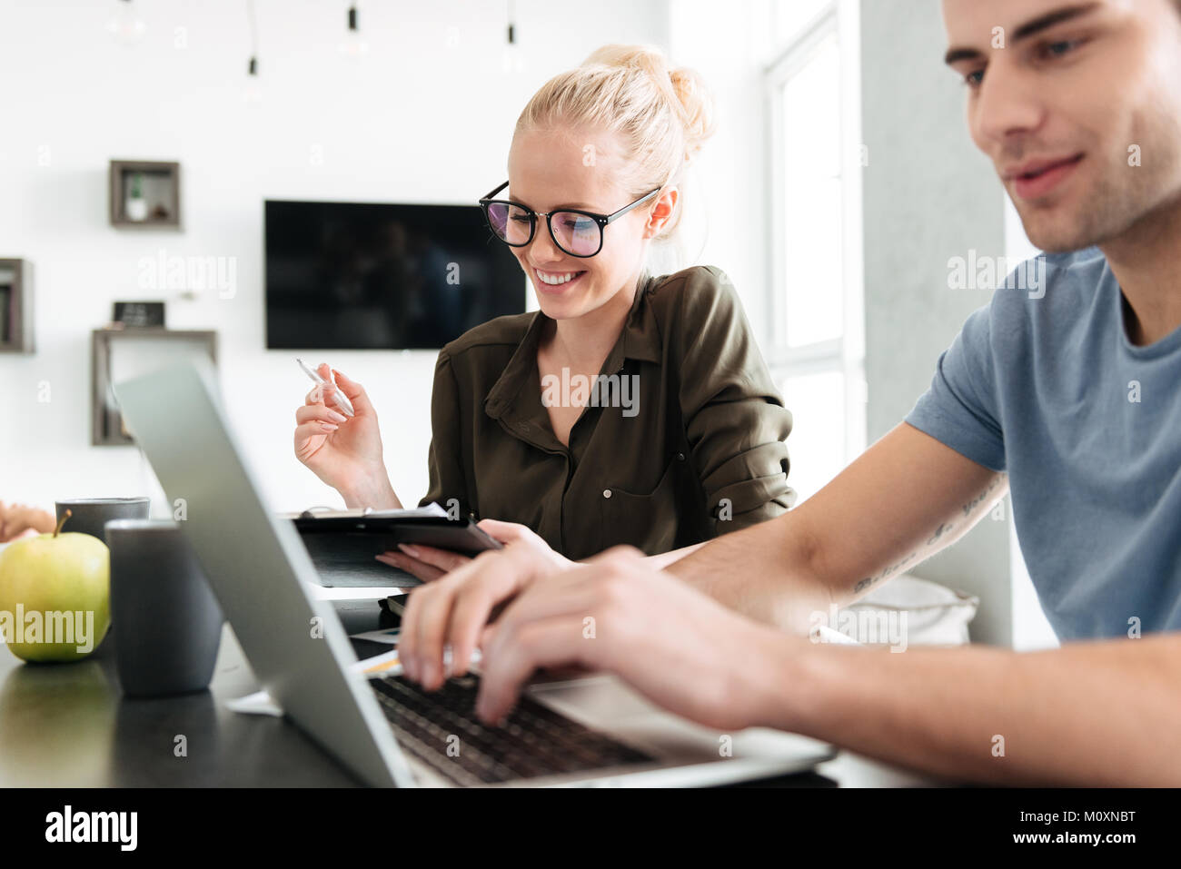 Young busy lovely couple, blonde woman in glasses and concentrated man ...
