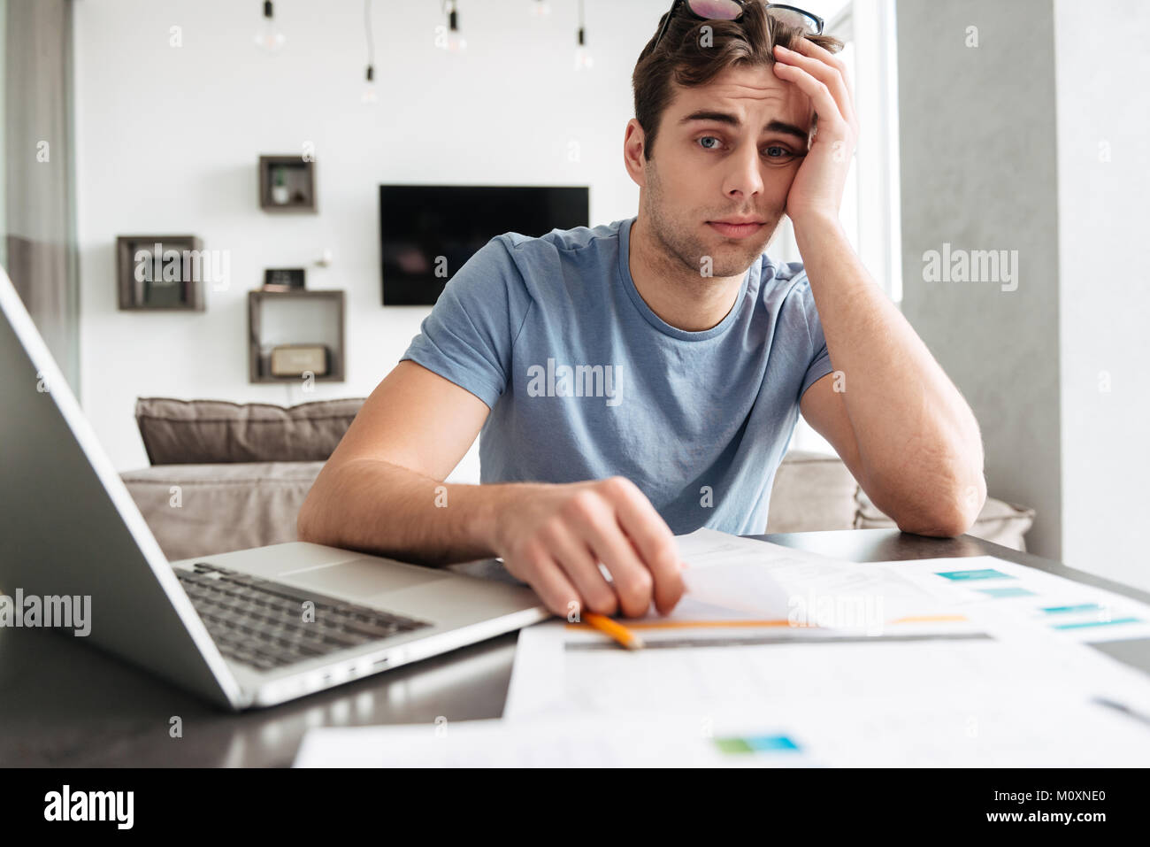 Tired busy man looking camera while working with laptop computer and ...