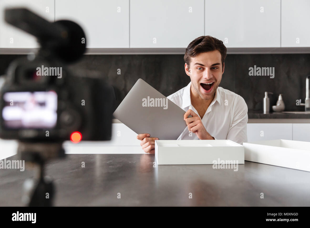 Photo of cheerful excited young man filming his video blog episode ...