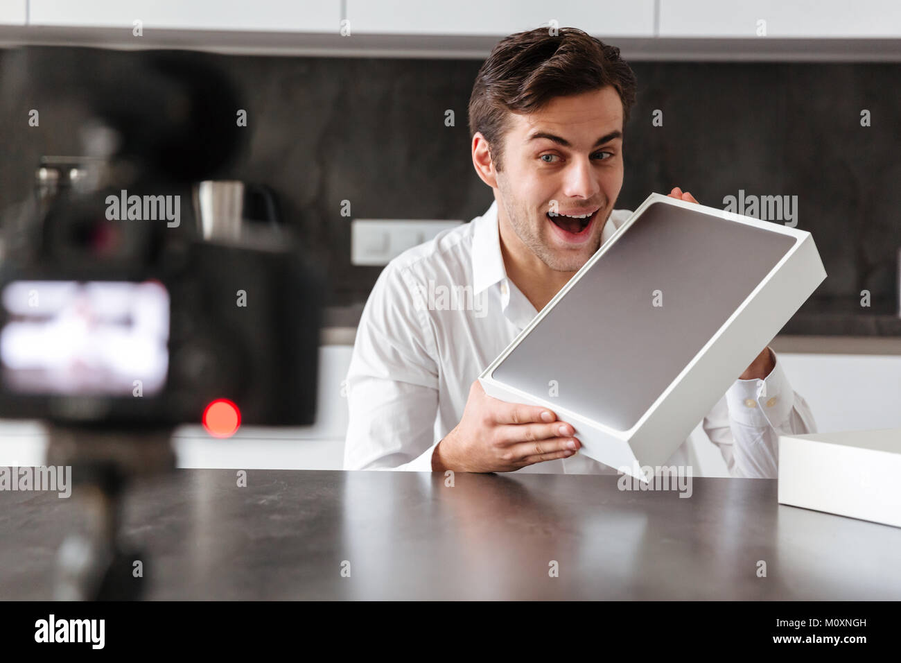 Photo of cheerful excited young man filming his video blog episode ...