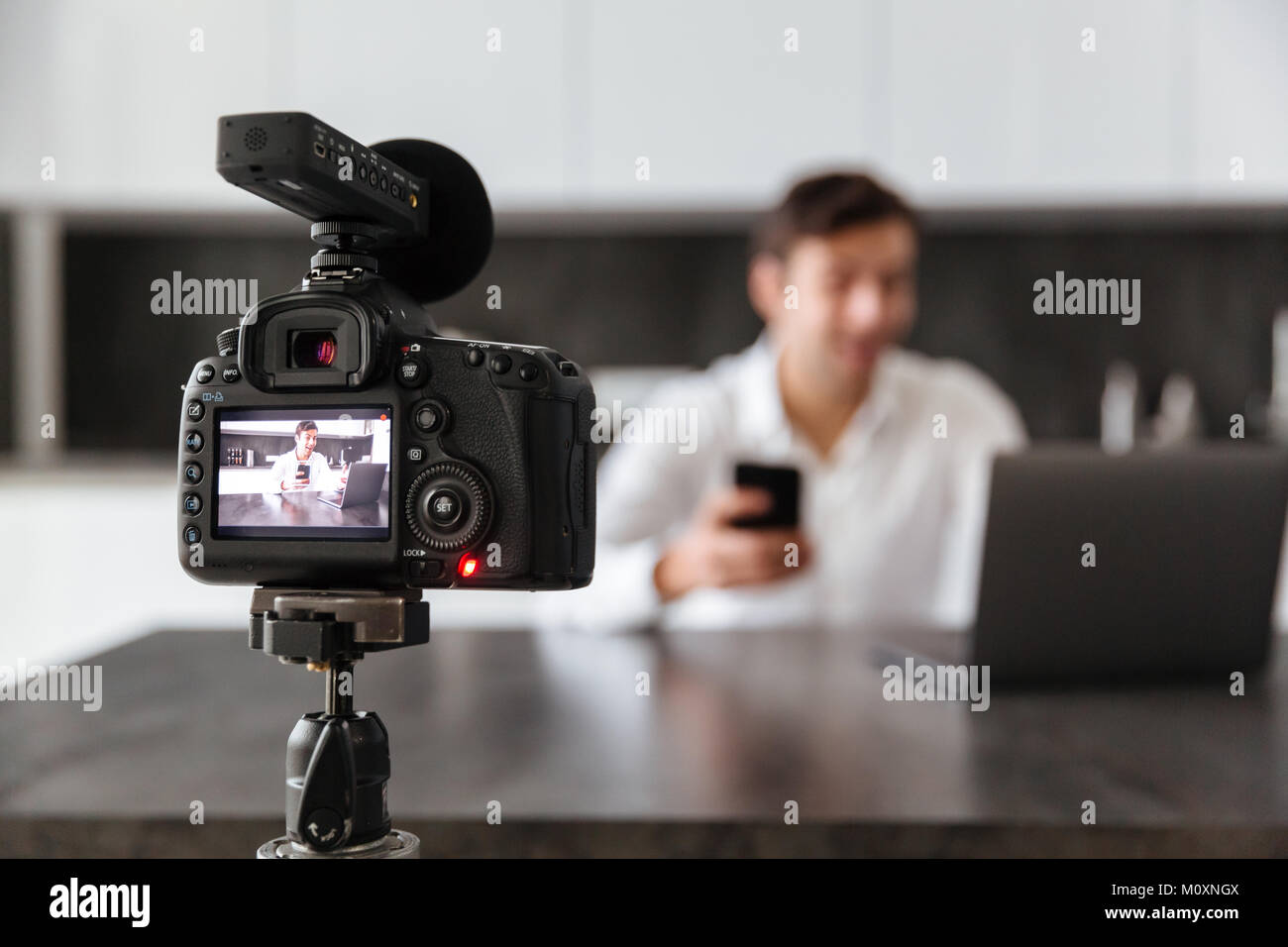 Concentrated young man filming his video blog episode about new tech ...