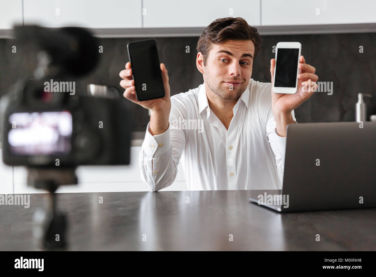 Handsome young man filming his video blog episode about new tech ...