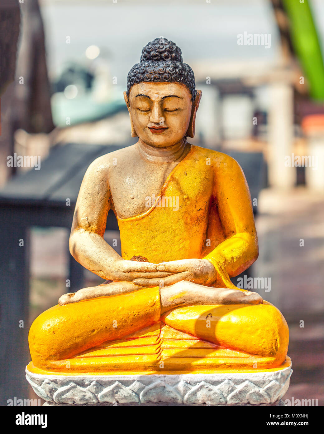 Colored golden Buddha statue outside of temple in bright sunlight ...