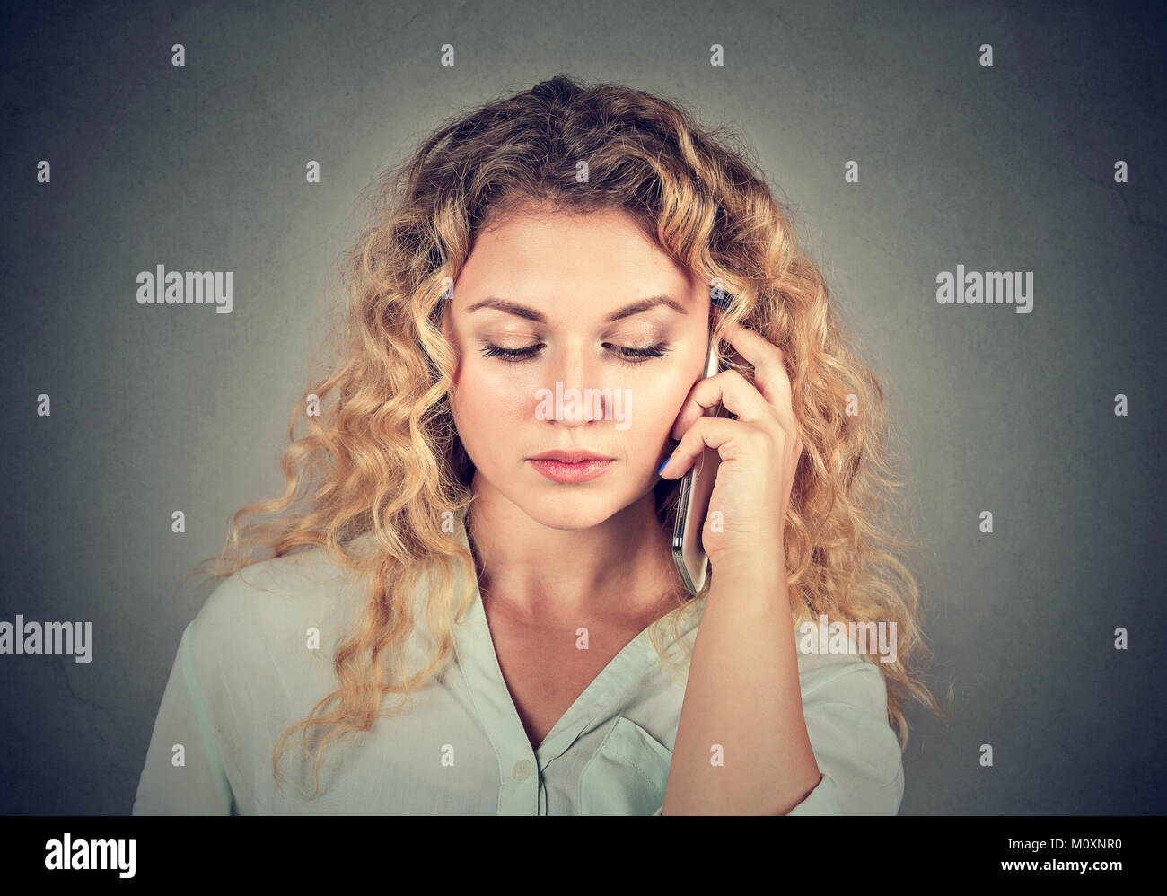 Young woman looking sad and lonely while having phone call to help line ...