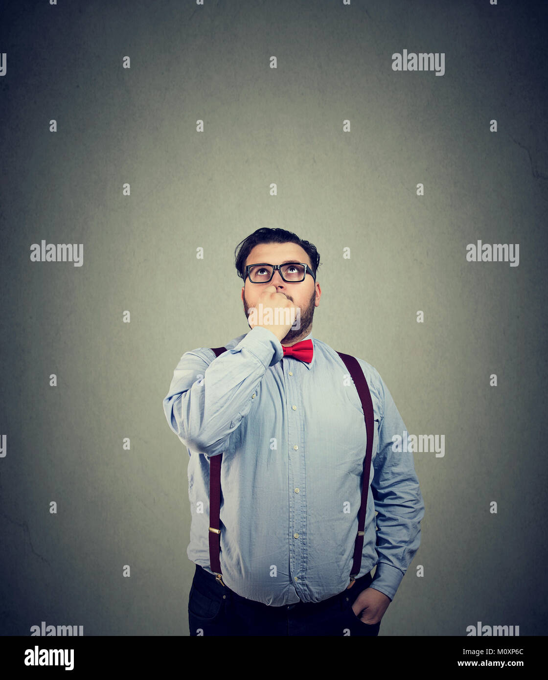 Young man in eyeglasses looking up and thinking thoroughly making ...