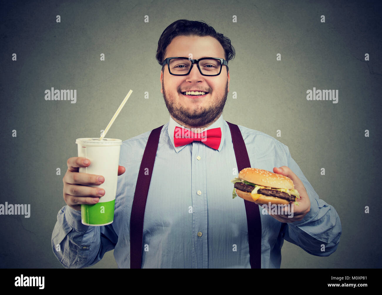 Young happy man looking excited while having burger and soda looking at ...