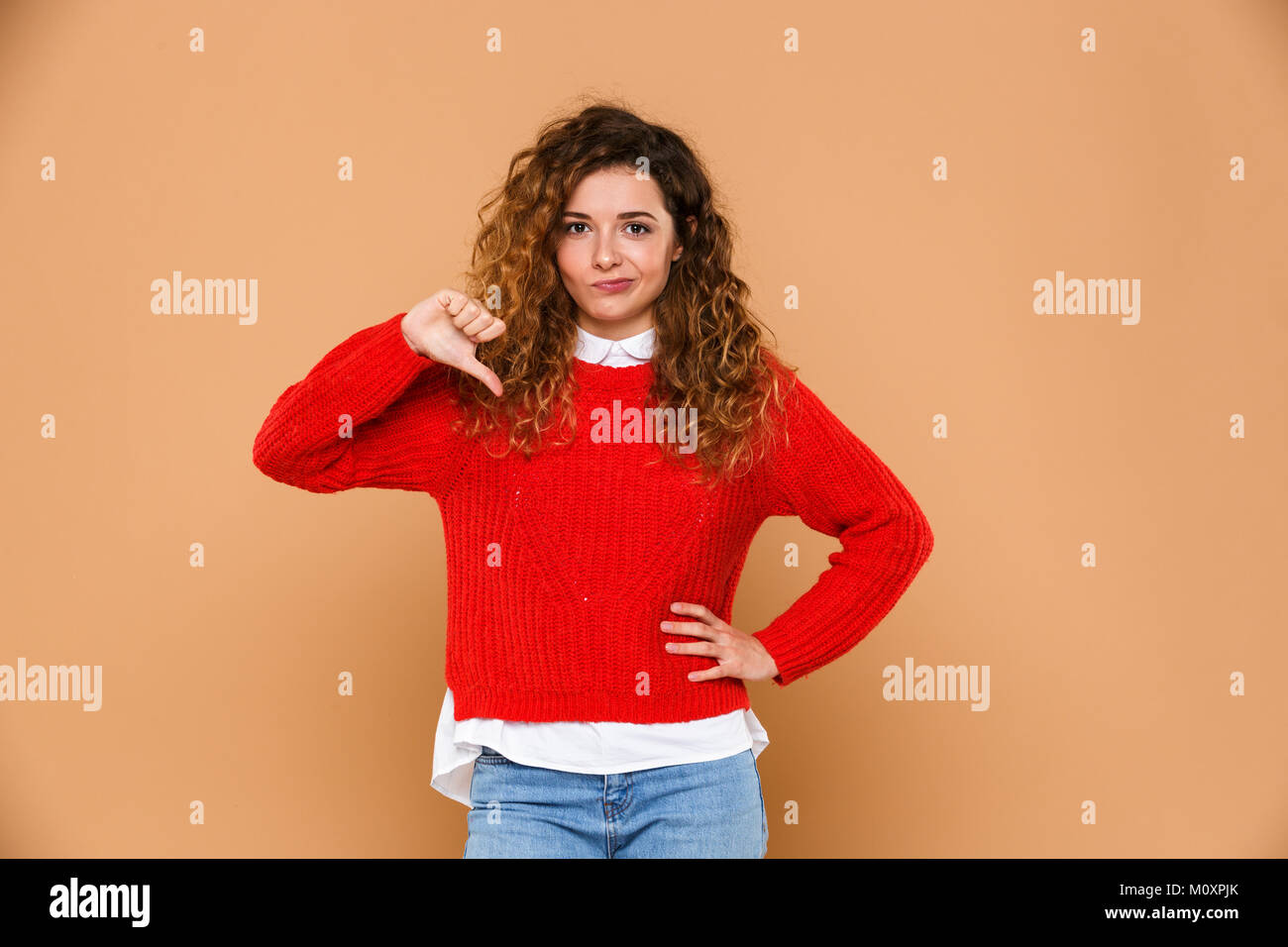Portrait of an upset disappointed girl standing and showing thumbs down ...