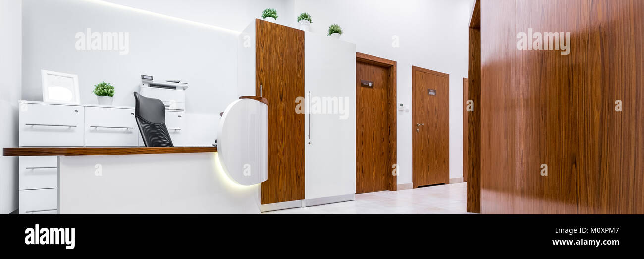 Panoramic view of modern reception in clinic with wooden doors and desk ...
