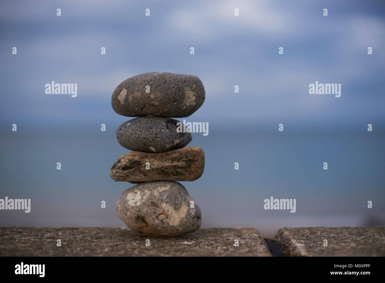 Arranged pile of four stones on a beach wall Stock Photo - Alamy