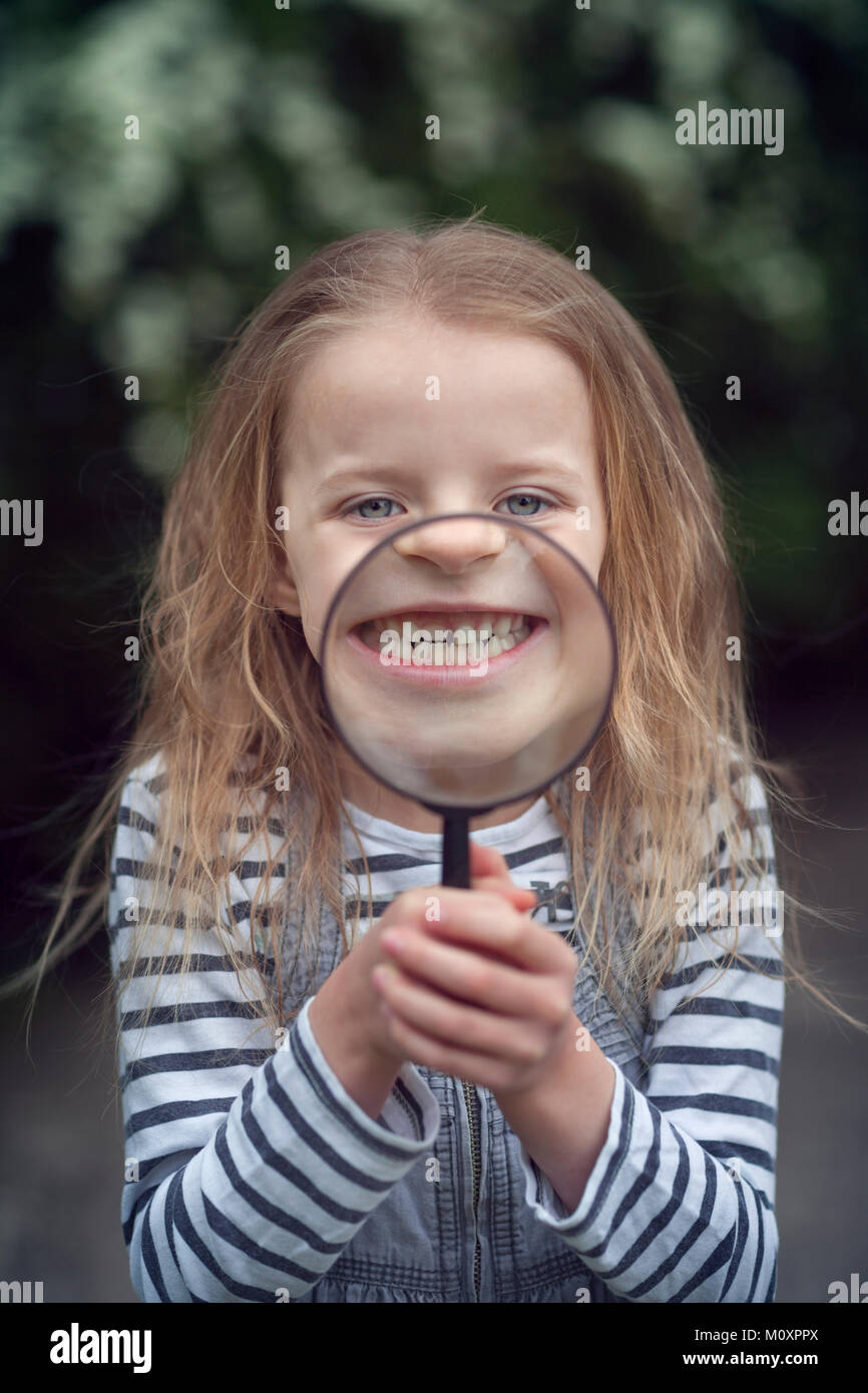 Child pulling silly face behind a magnifying glass Stock Photo - Alamy