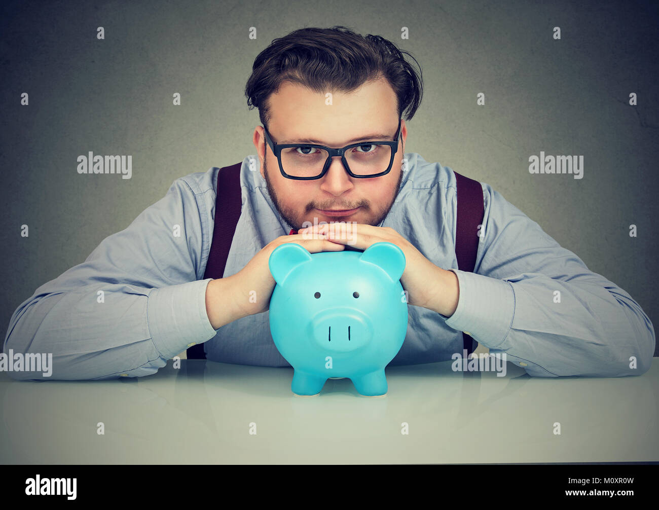 Content young man in formal outfit posing with money box saving money ...