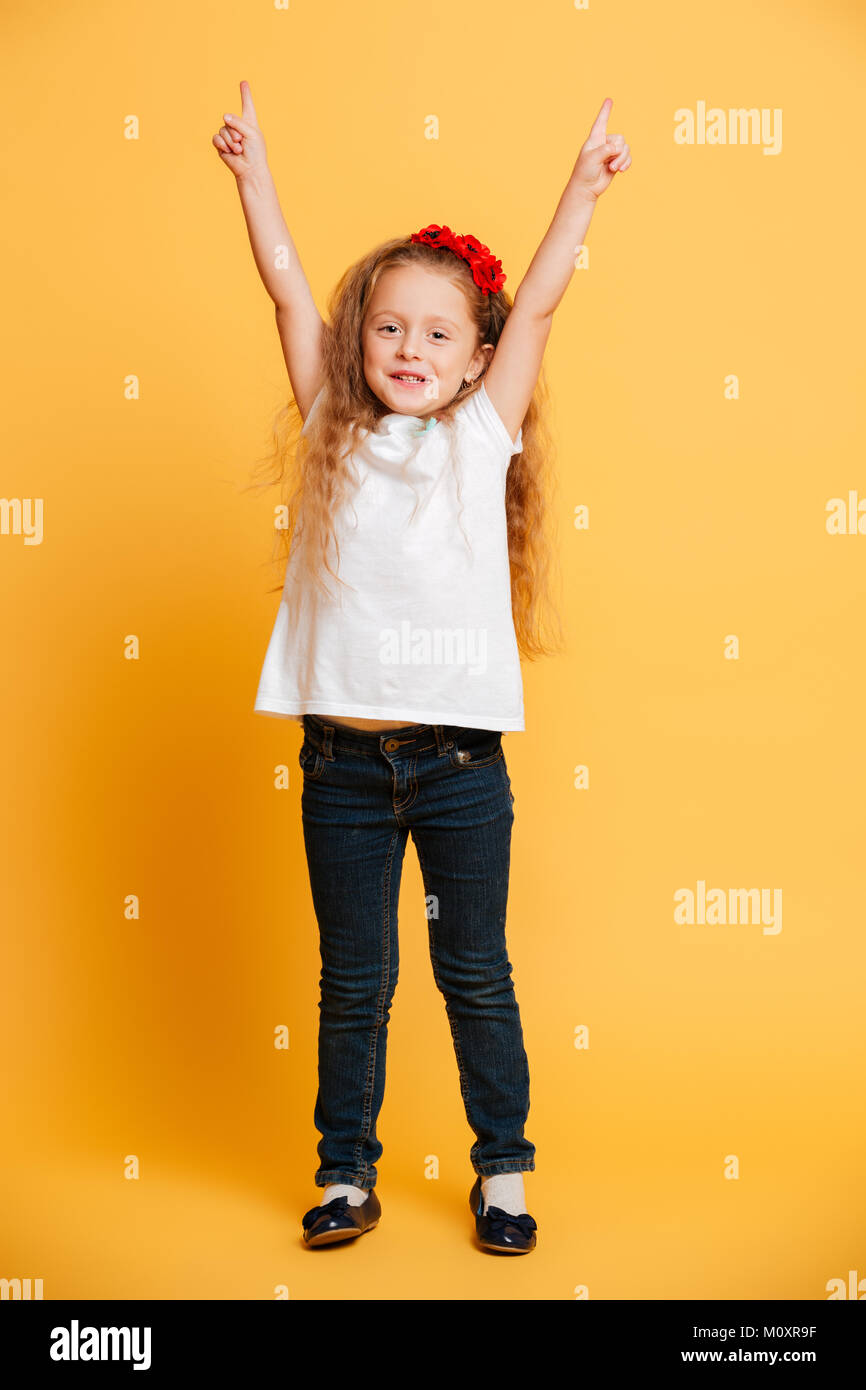 Photo of little cute girl child standing isolated over yellow ...