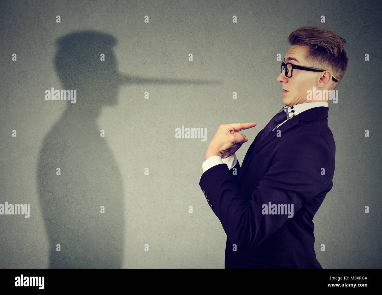 Side view of man in suit pointing at himself looking at shadow with ...