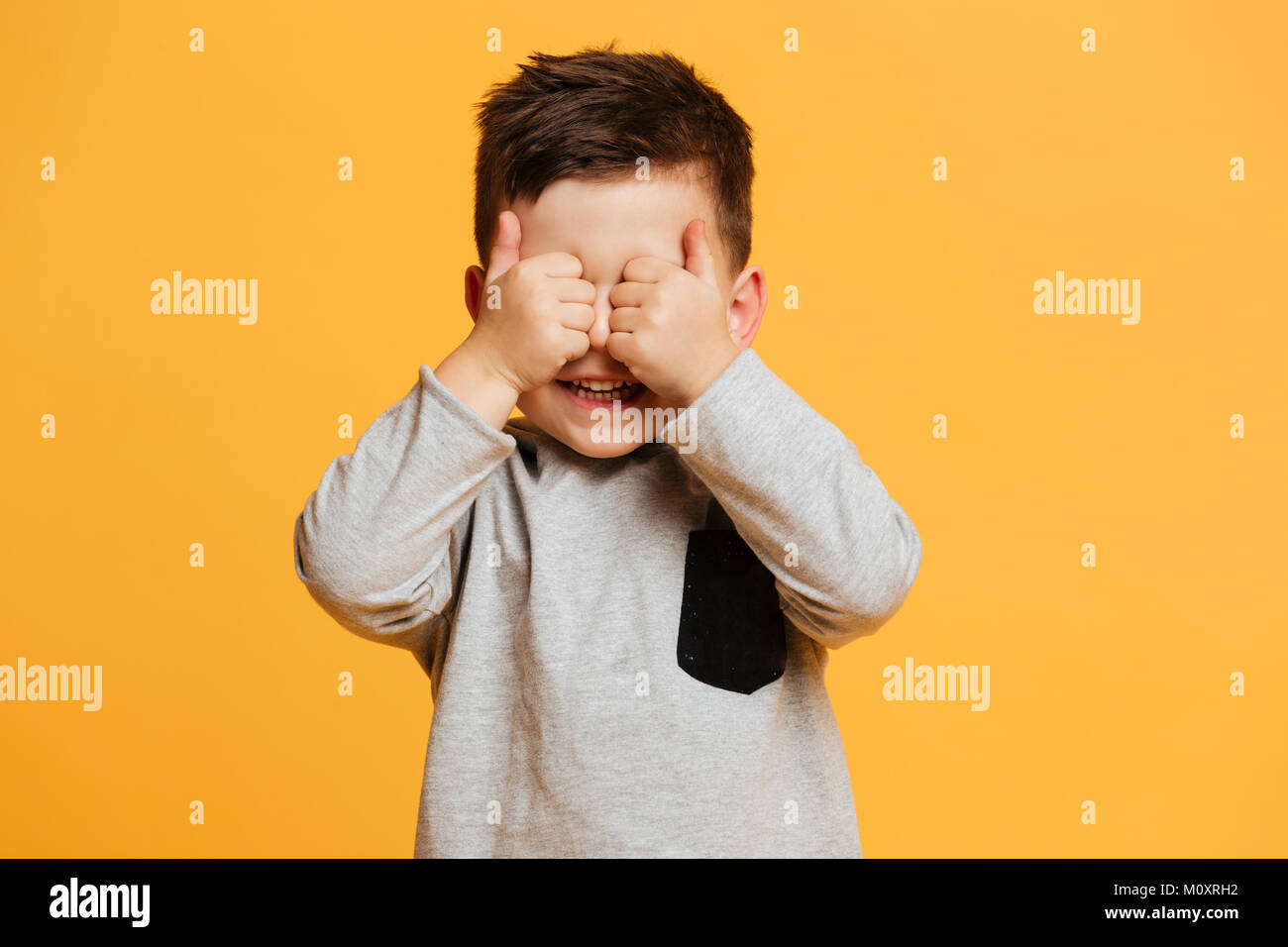 Picture of smiling cute little boy child standing isolated over yellow ...