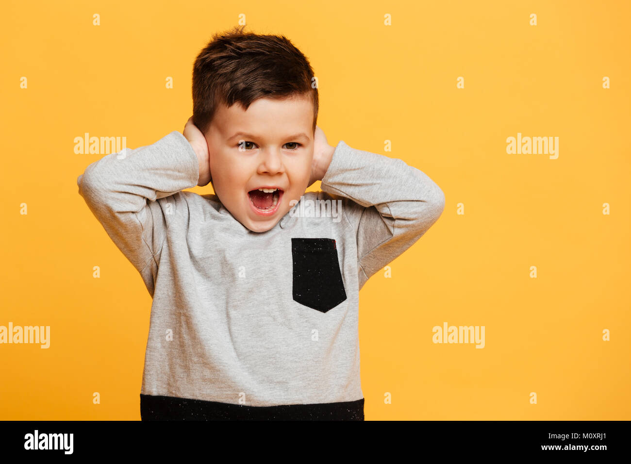 Picture of screaming little boy child standing isolated over yellow ...