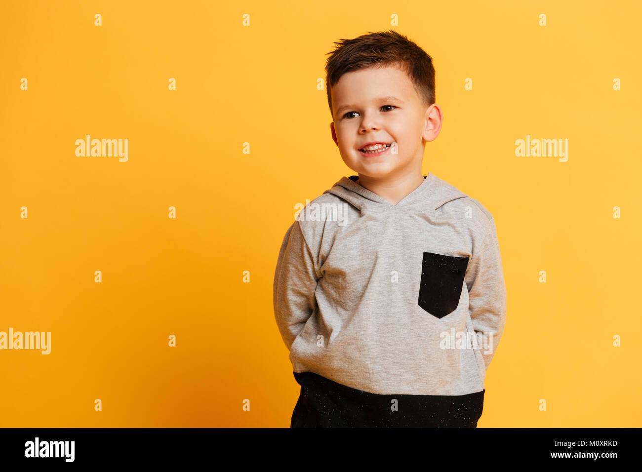 Photo of smiling little boy child standing isolated over yellow ...