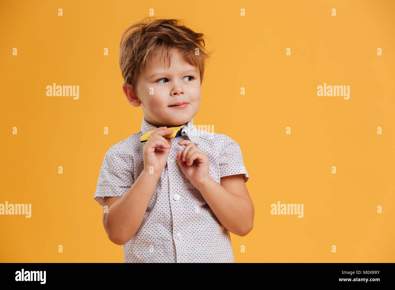 Image of thoughtful little boy child standing isolated over yellow ...