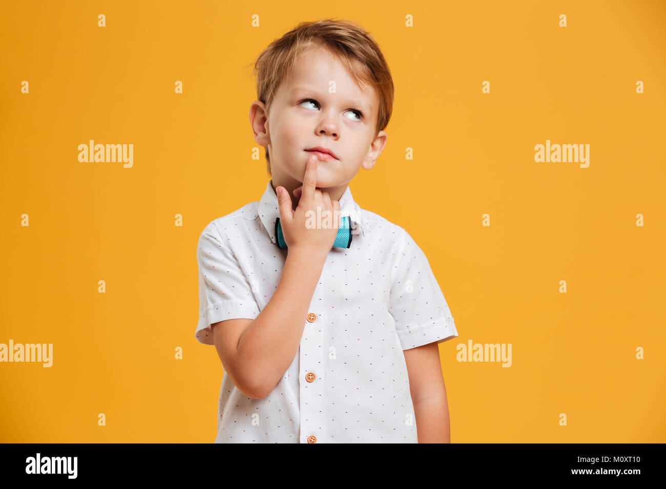 Picture of thinking little boy child standing isolated over yellow ...