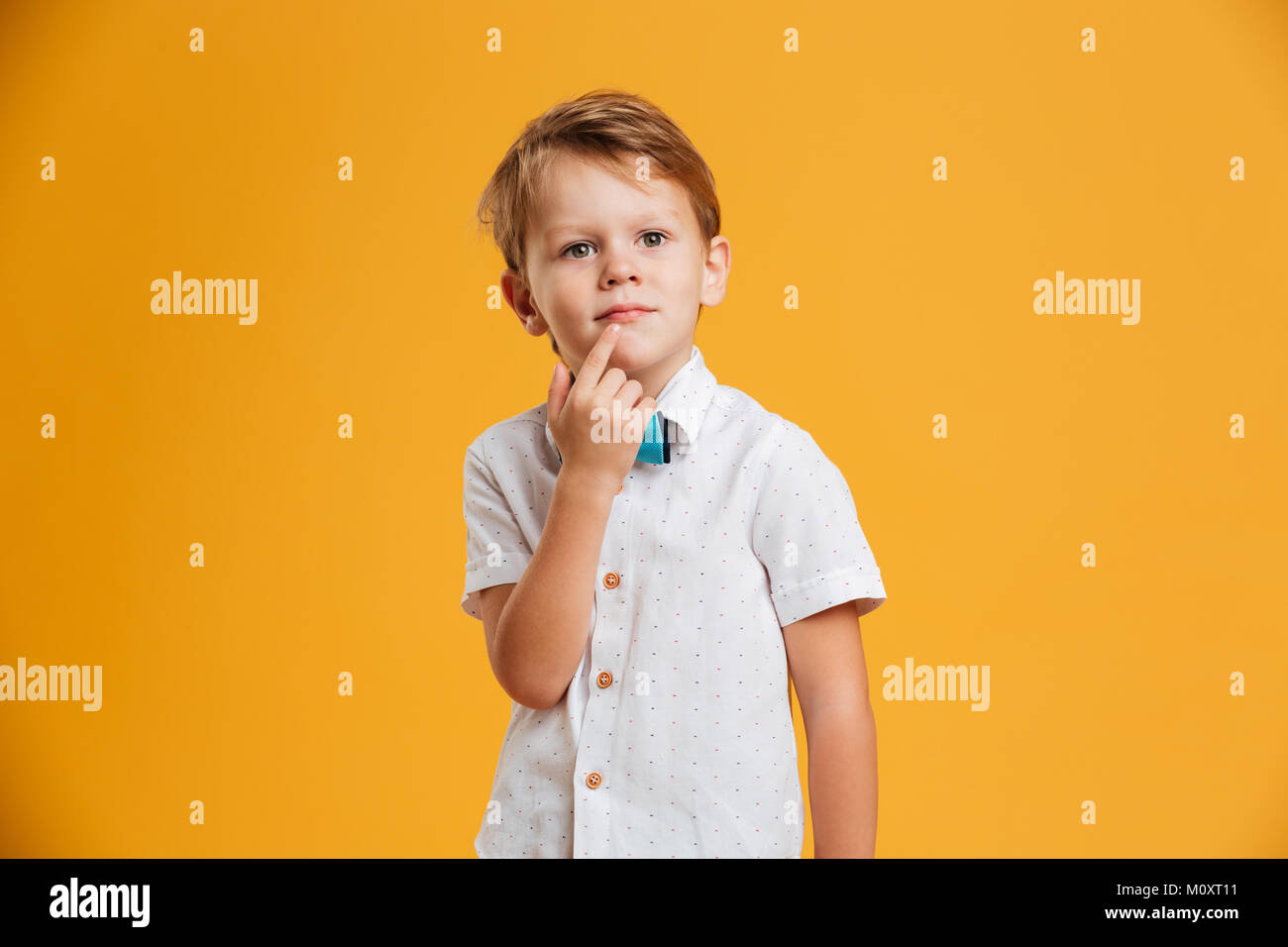 Picture of thinking little boy child standing isolated over yellow ...