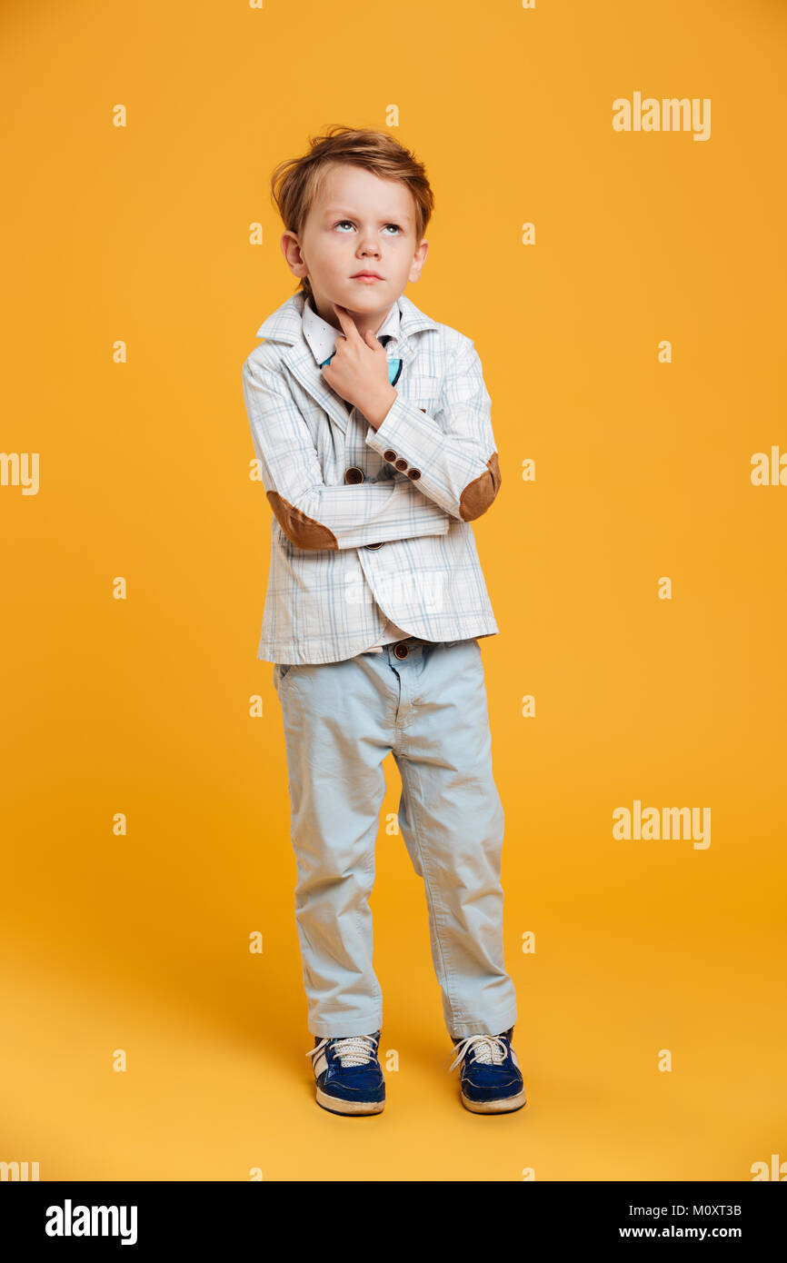 Image of thoughtful little boy child standing isolated over yellow ...