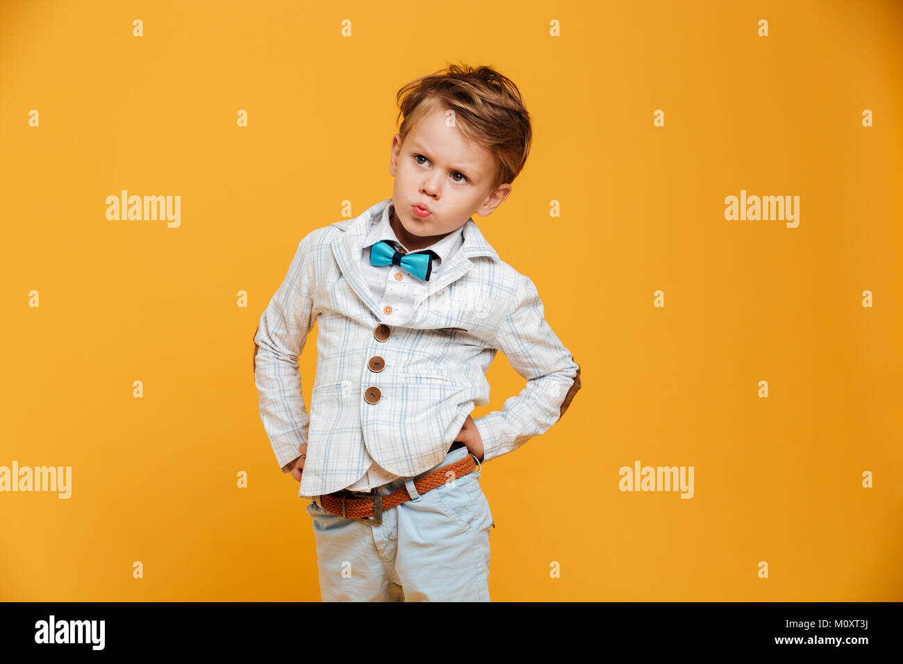 Image of thoughtful little boy child standing isolated over yellow ...