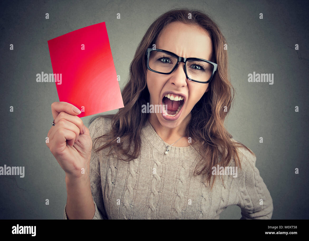Young woman in eyeglasses holding red paper and screaming angrily at ...