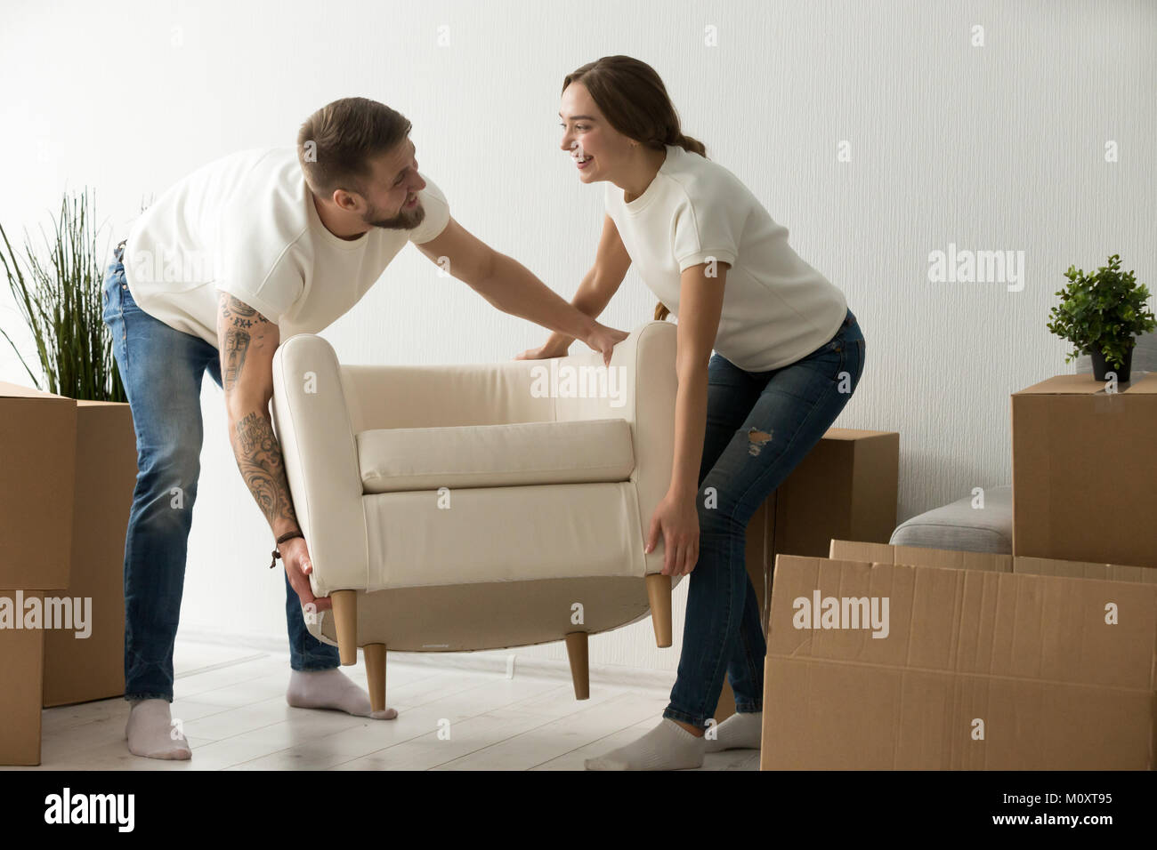 Young couple carrying chair together, placing furniture in new h Stock ...
