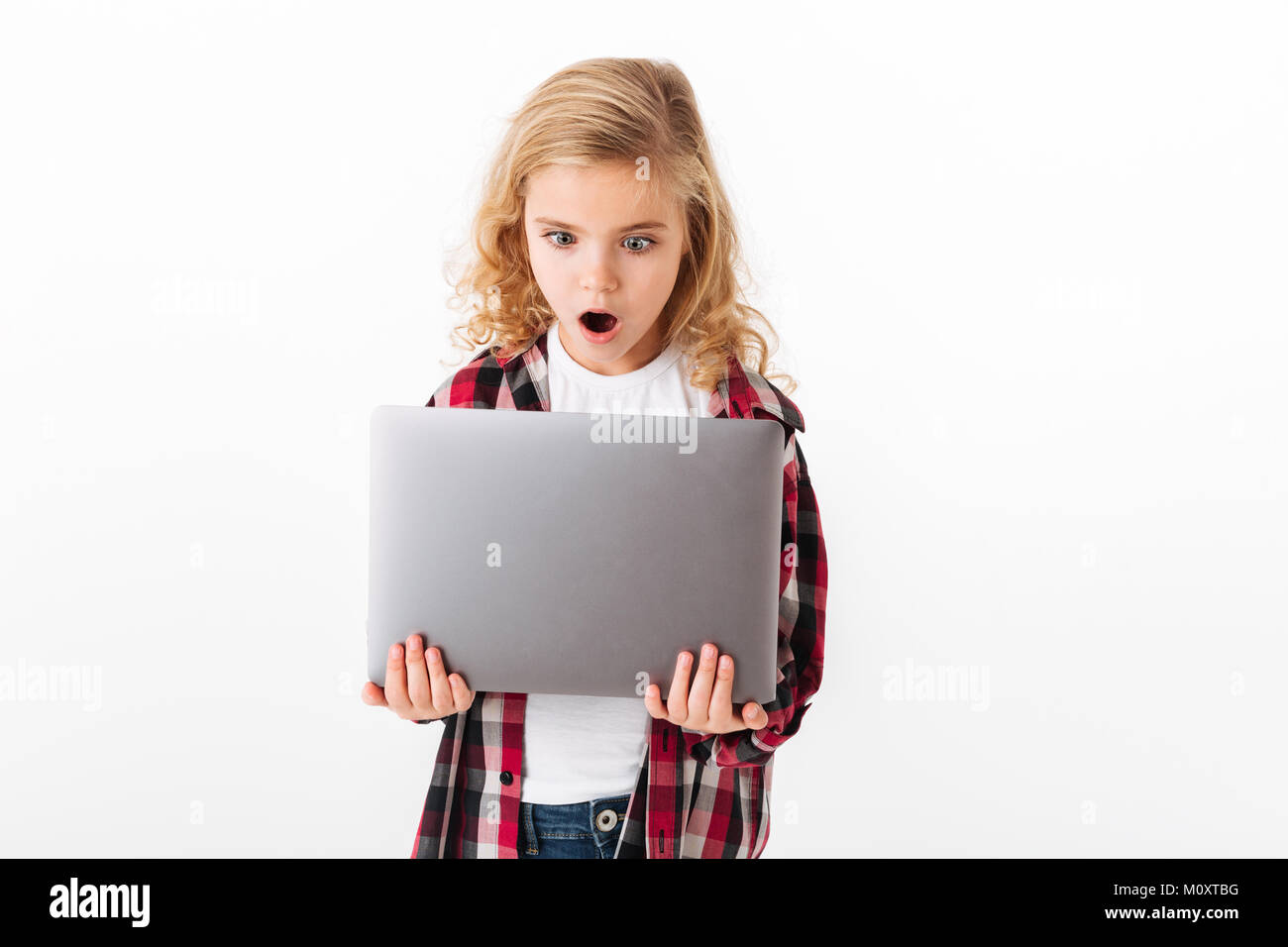Portrait of an astonished little girl looking at laptop computer screen ...