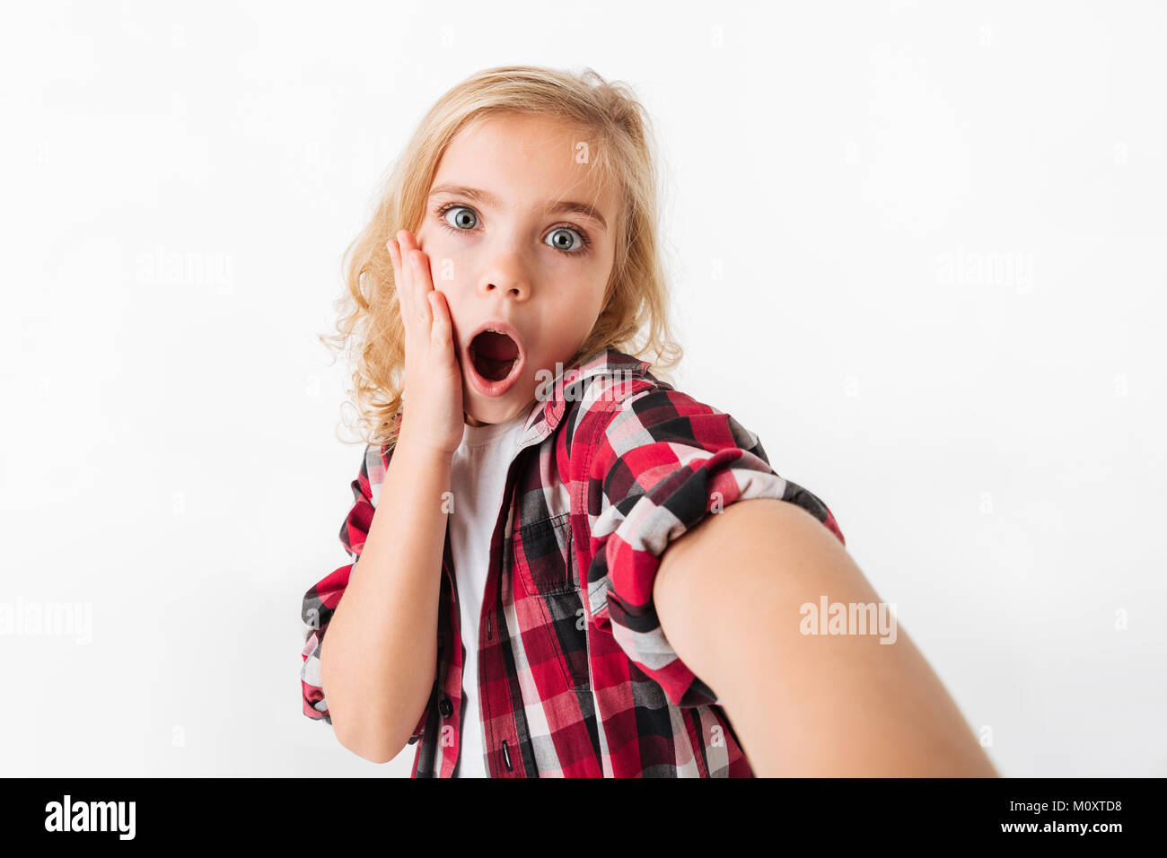 Portrait of a surprised little girl taking a selfie isolated over white ...