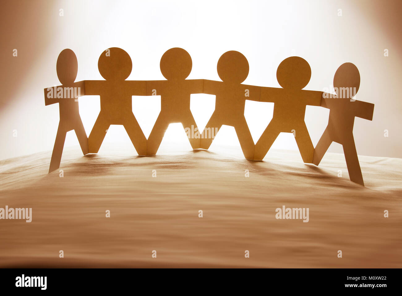 Team of paper chain people in a row holding hands Stock Photo - Alamy