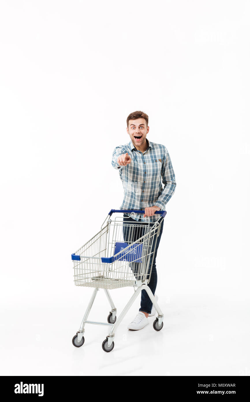 Full length portrait of a happy man walking with a shopping trolley and ...