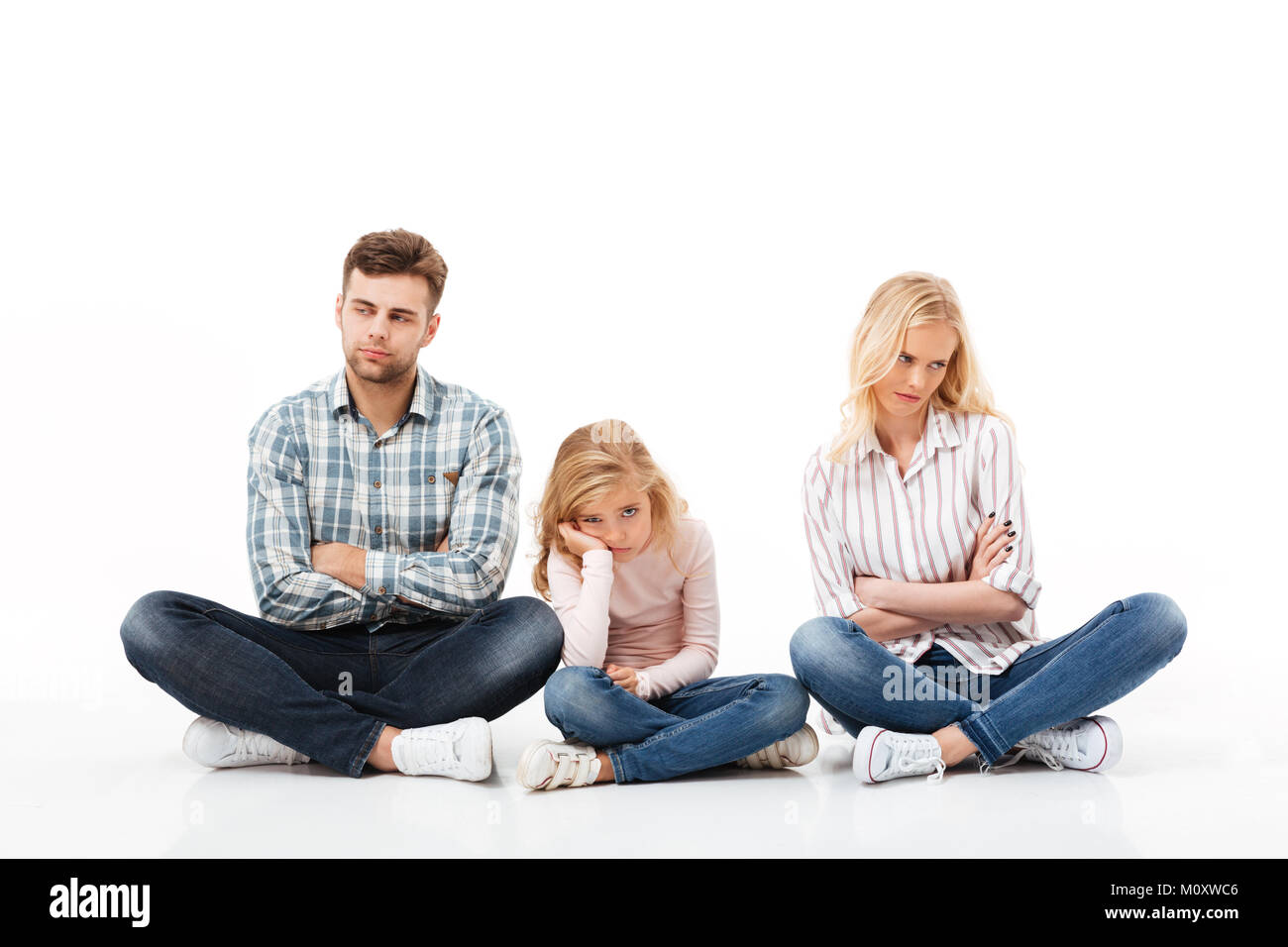 Portrait of an upset family sitting together isolated over white ...
