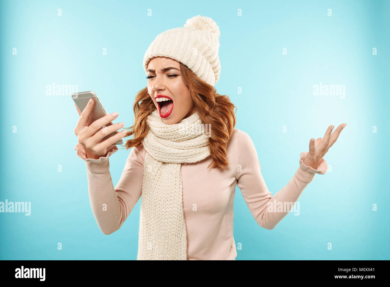 Portrait of an angry furious girl dressed in hat and scarf looking at ...