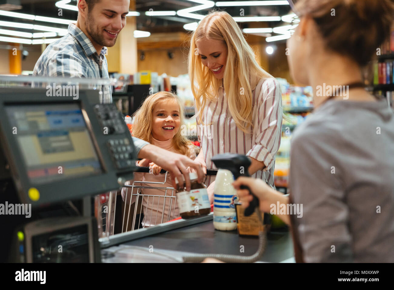 Happy family standing at the cash counter buying groceries at the ...