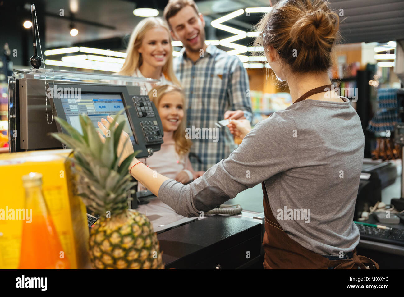 Beautiful family paying for their groceries with a credit card while ...
