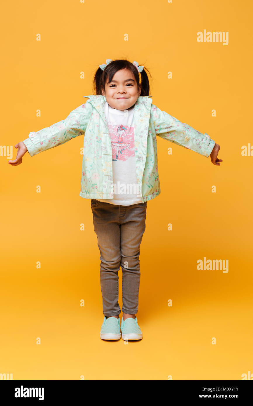 Photo of confused cute little girl child standing isolated over yellow ...