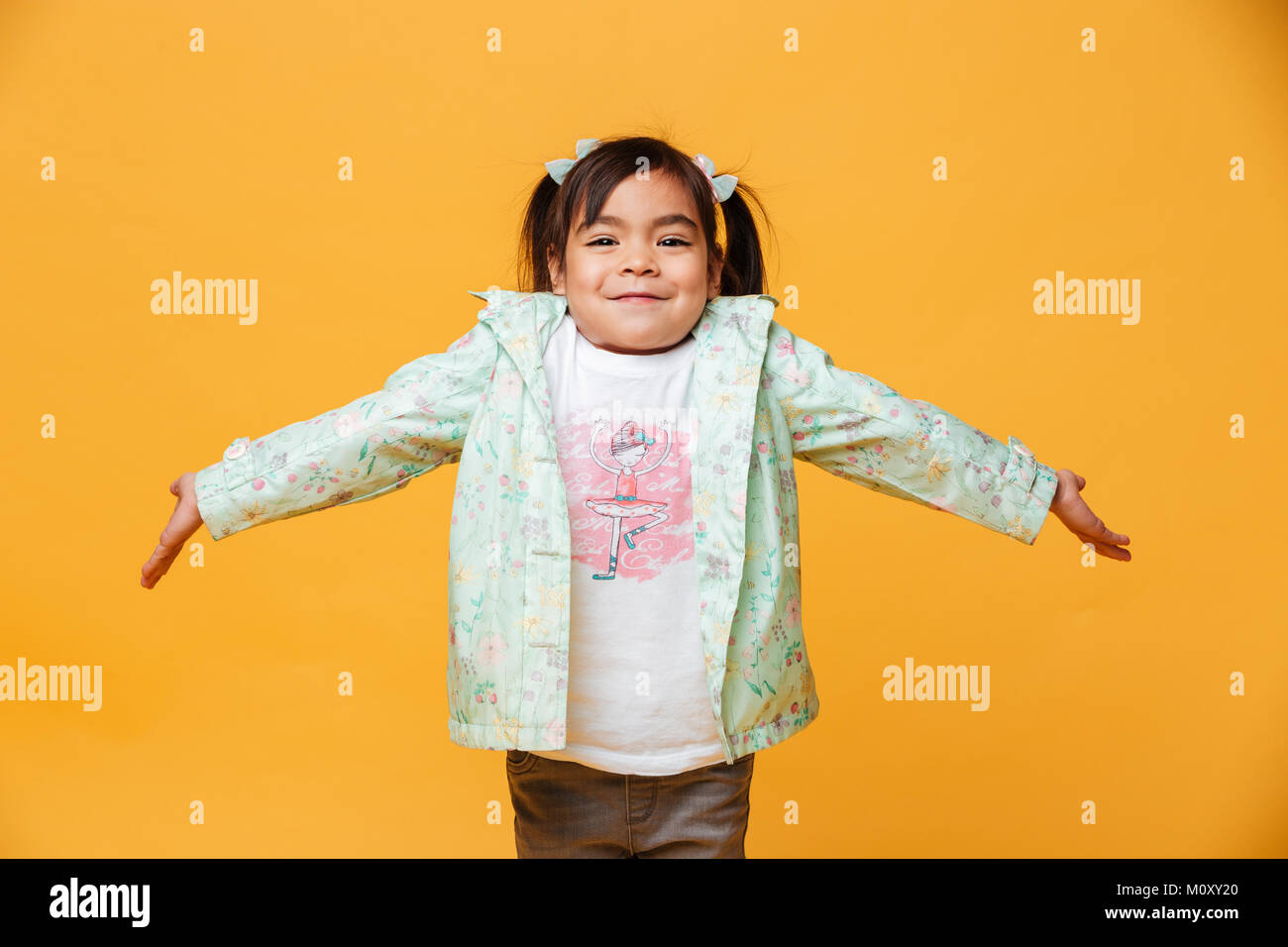 Photo of confused cute little girl child standing isolated over yellow ...