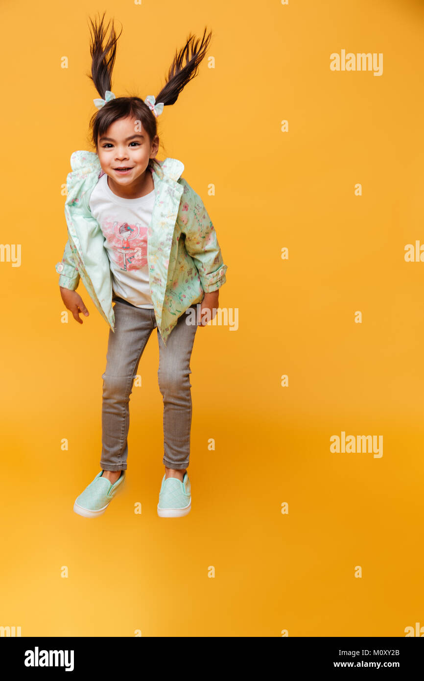 Picture of cheerful little girl child jumping isolated over yellow ...