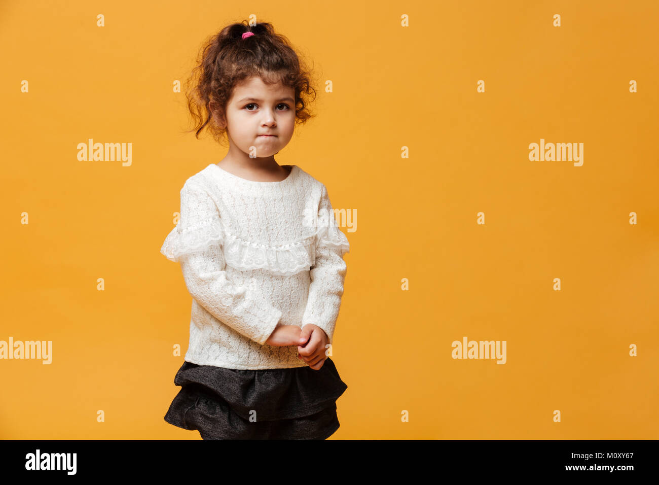 Photo of confused little girl child standing isolated over yellow ...