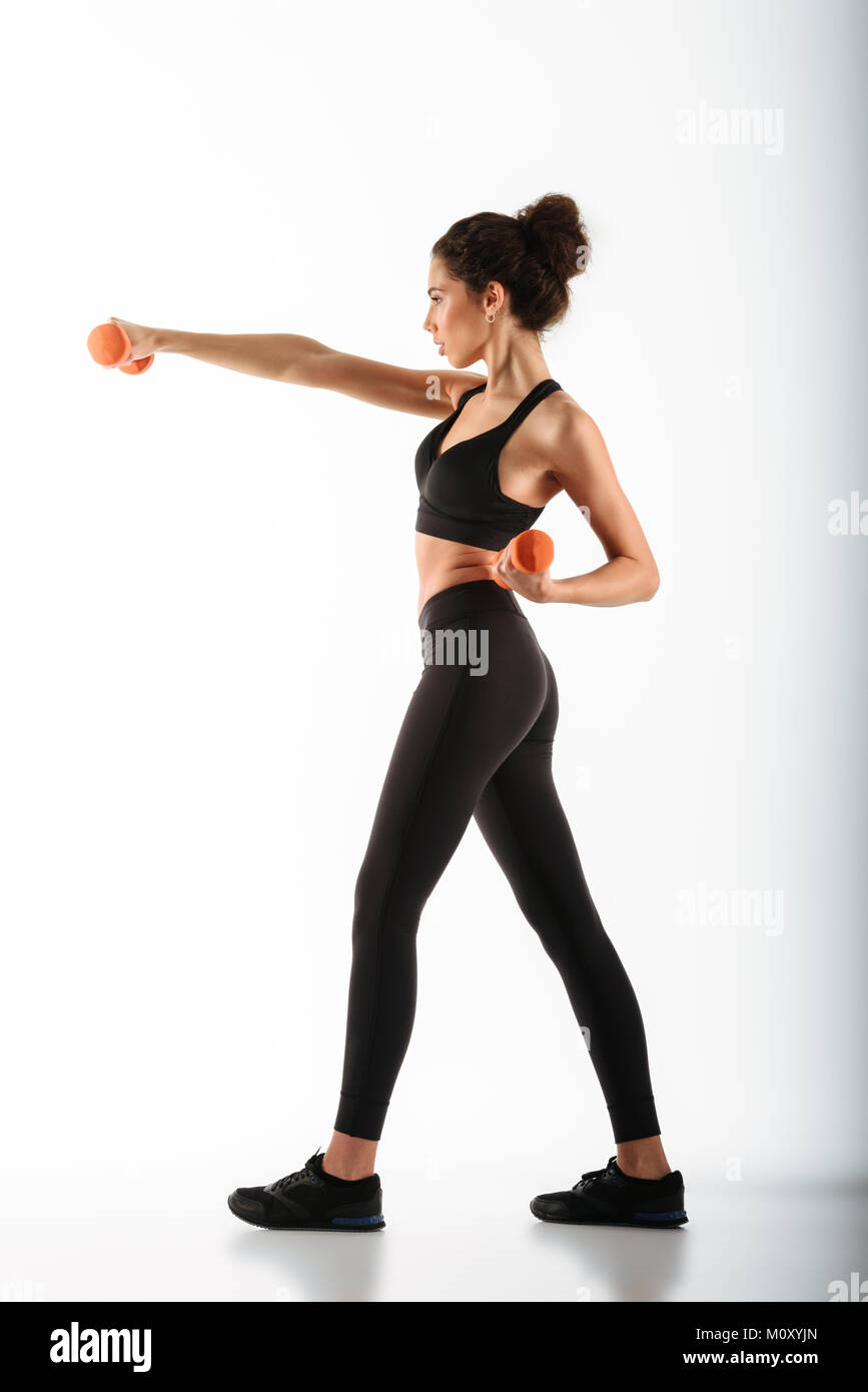 Full length image of Concentrated fitness woman standing in profile and ...