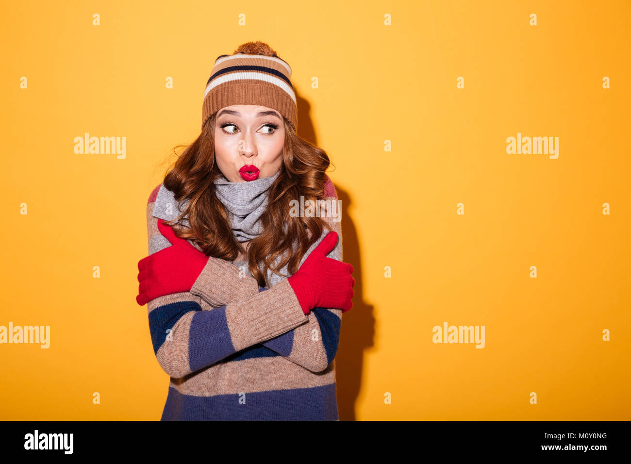 Portrait of a pretty frozen girl dressed in winter clothes looking away ...