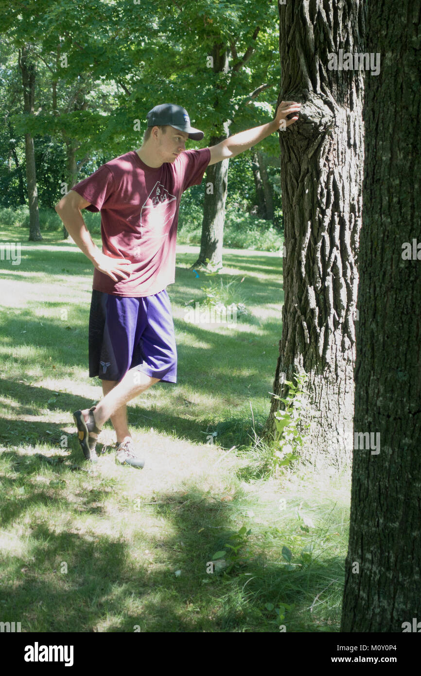 Boy leaning against tree hi-res stock photography and images - Alamy