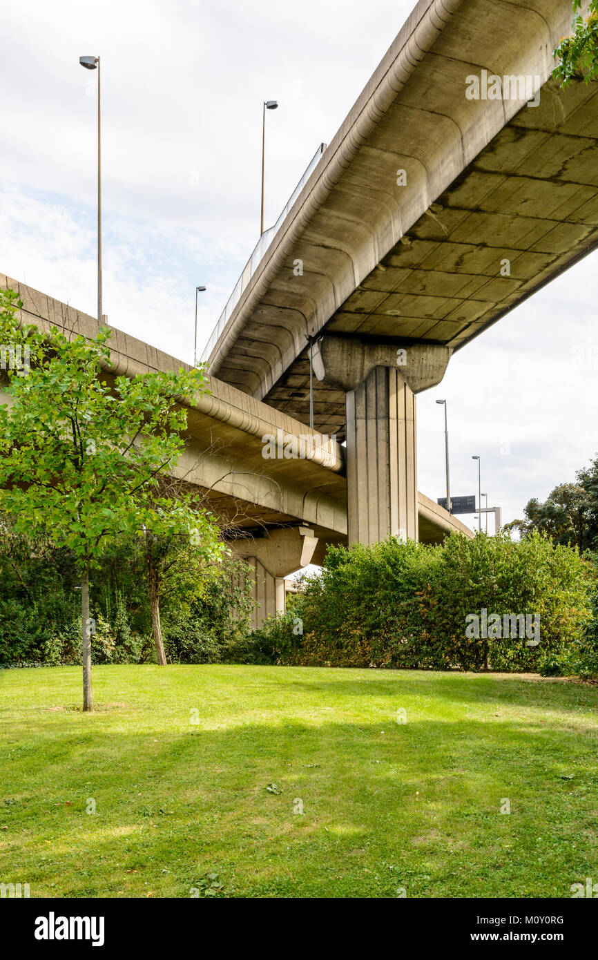 Two concrete highway ramps crossing above an empty public garden with a ...