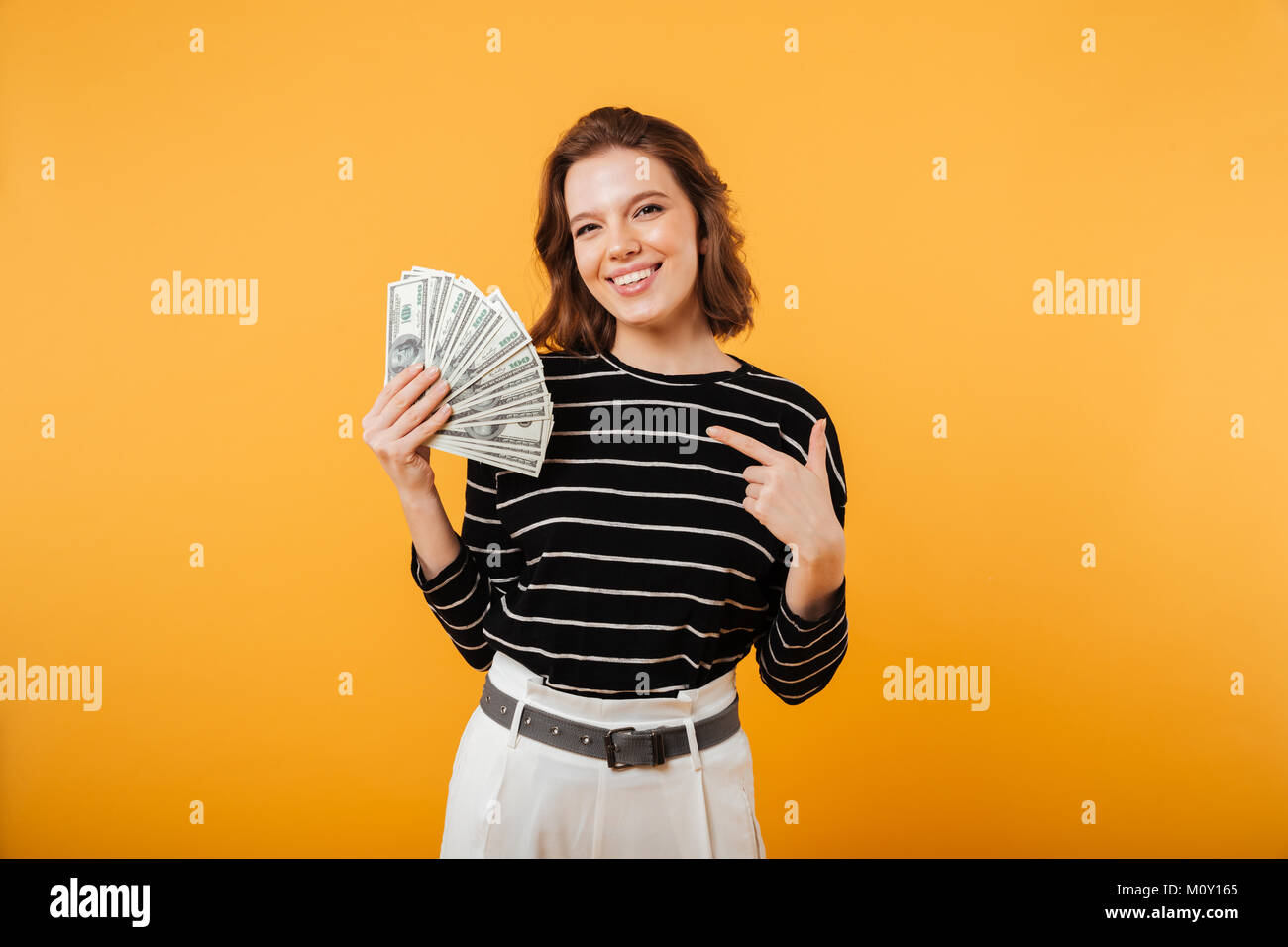 Portrait of a happy woman pointing finger bunch of money banknotes and ...
