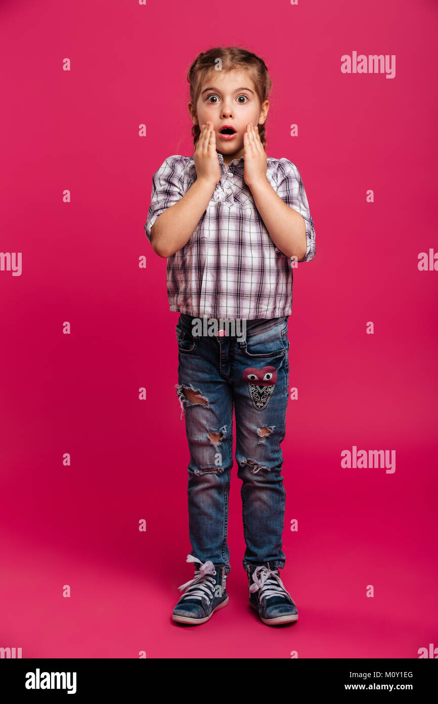 Photo of shocked cute little girl child standing isolated over pink ...