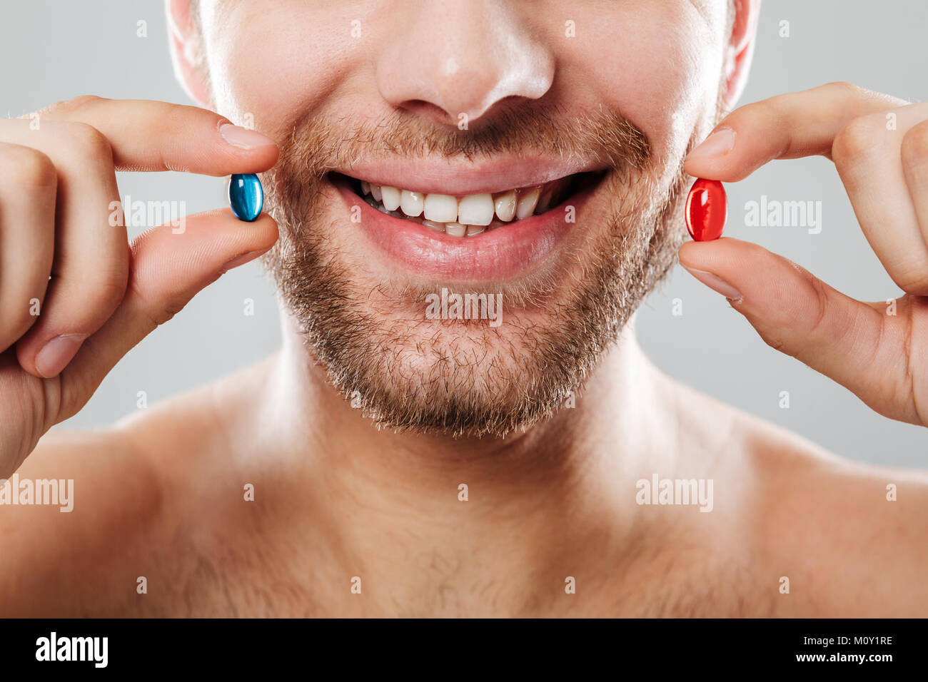 Close up portrait of a smiling man holding two capsules at his face ...