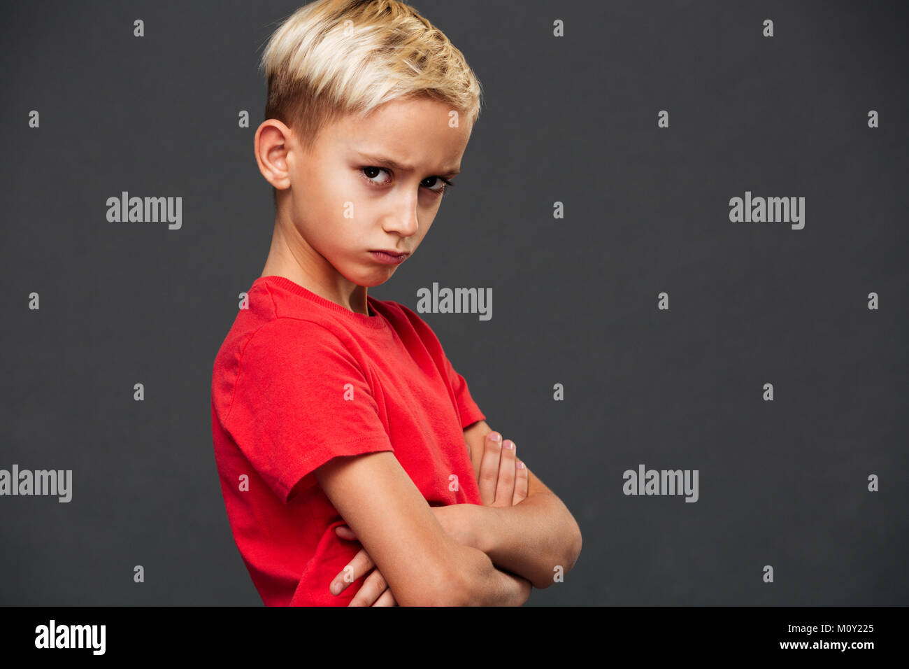 Photo of angry little boy child standing isolated over grey background ...