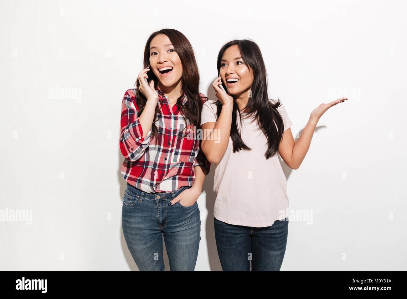 Image of asian women sisters talking by their mobile phones standing ...